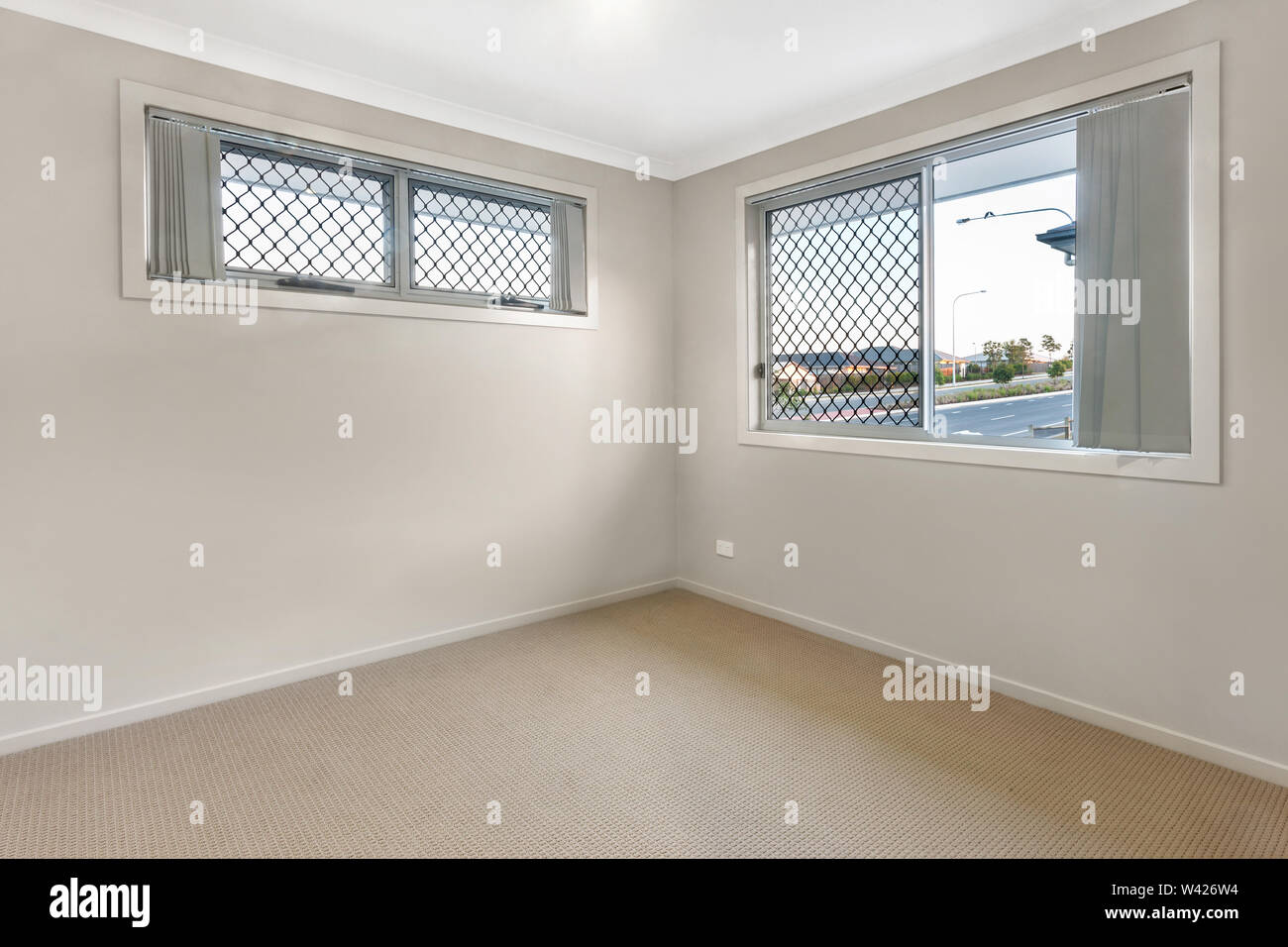 Carpeted bedroom with two windows Stock Photo - Alamy
