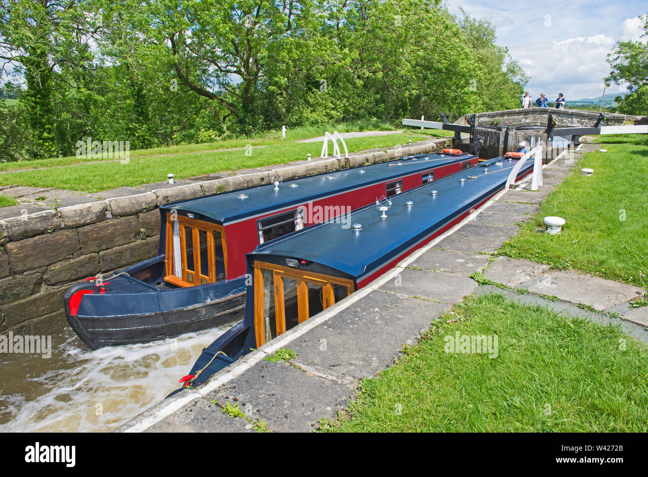 Two narrowboats traveling through a deep lock in English rural ...