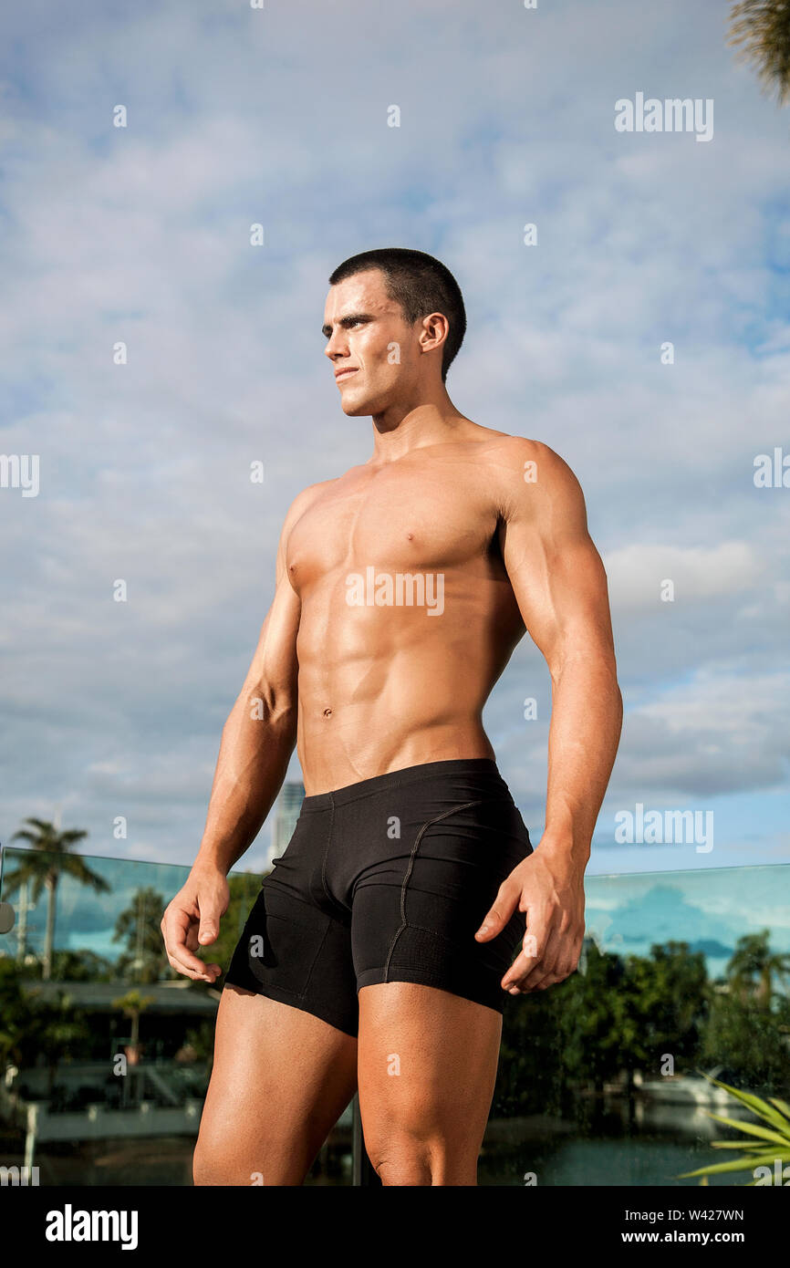 Body builder standing with black short , outside area near lake and ...