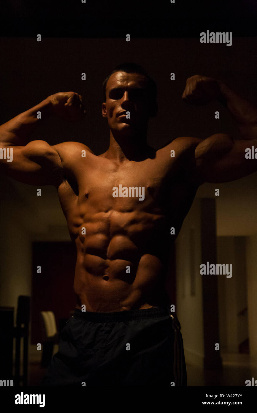 Trainer with healthy and shiny arms, night time scene at inside room of ...