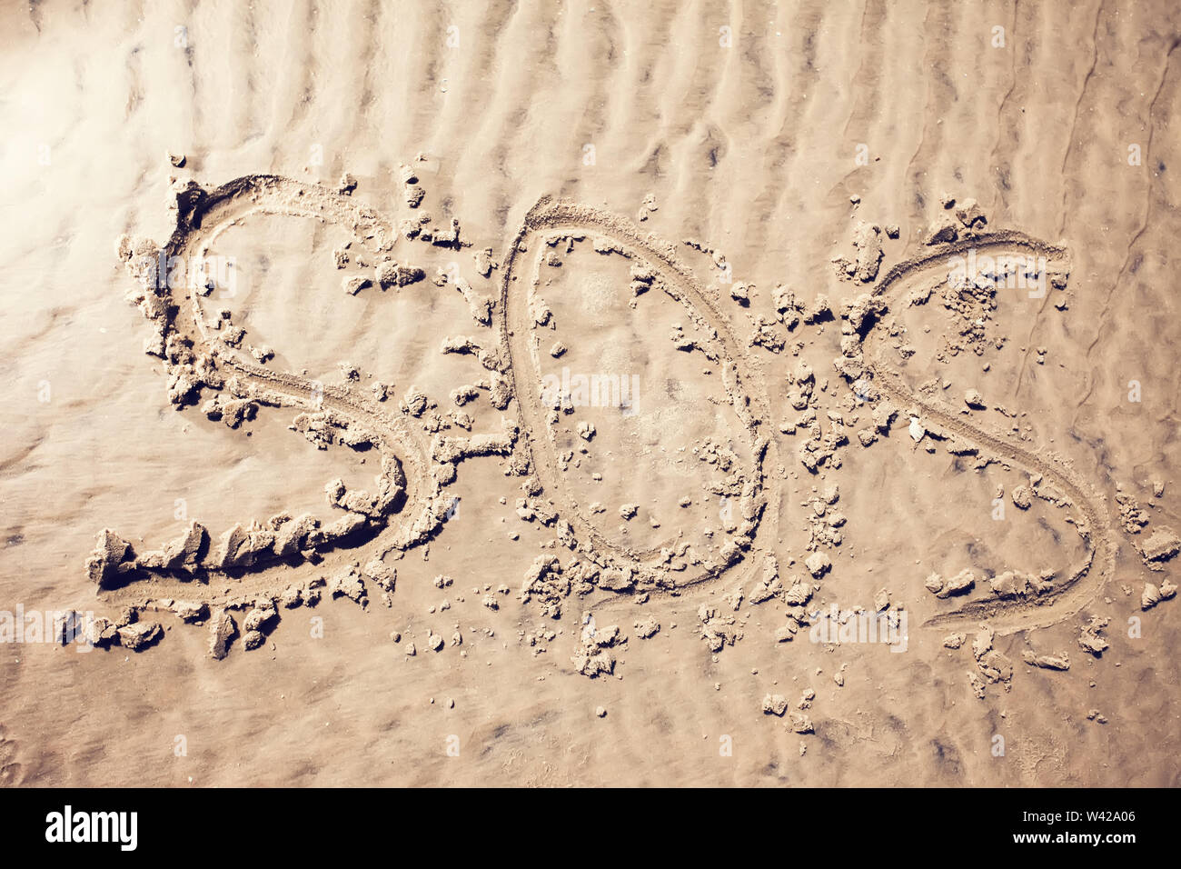 Sos sign write by hand on sand Stock Photo - Alamy