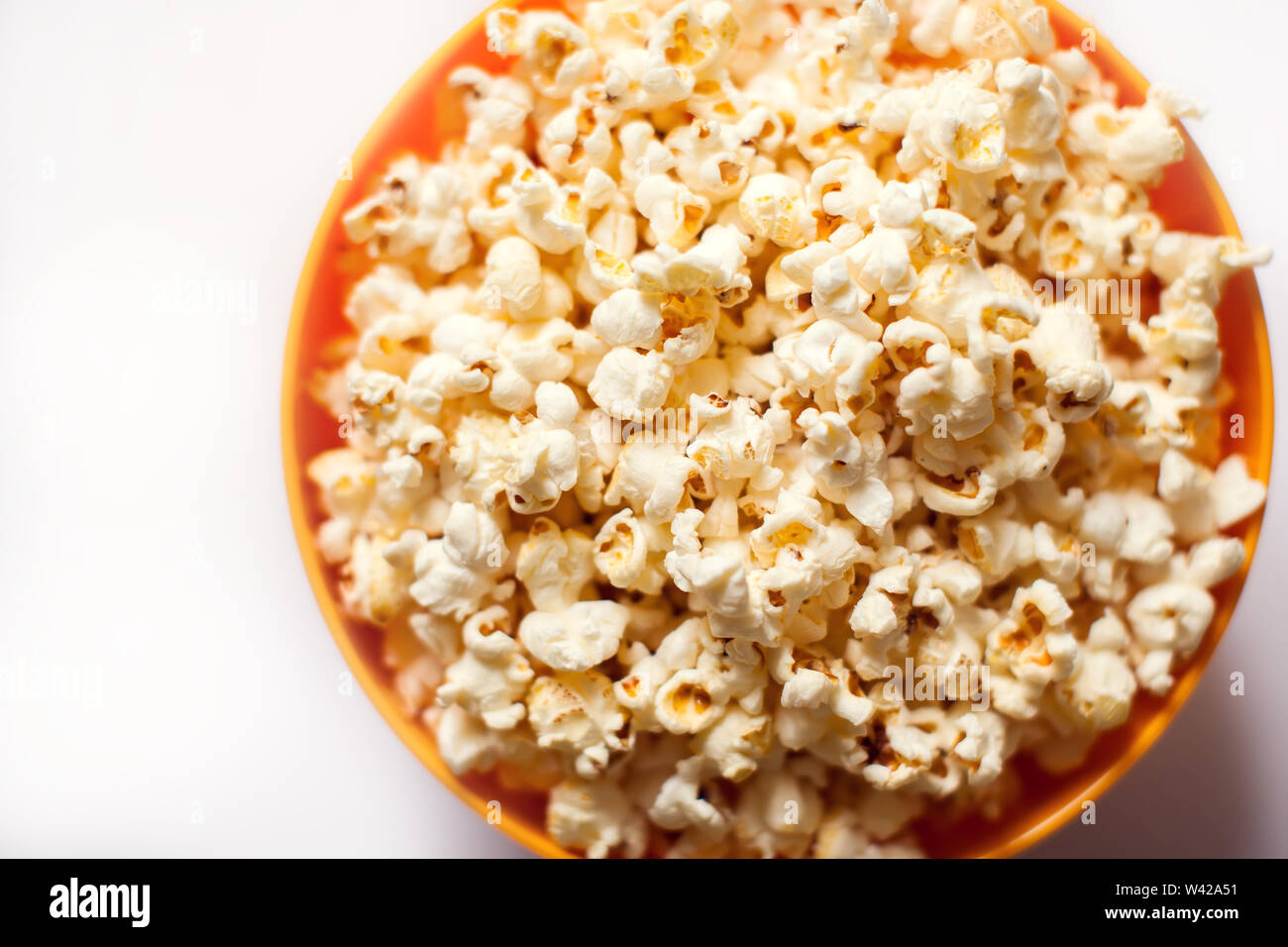 An orange bowl with popcorn isolated on white background. Food concept ...