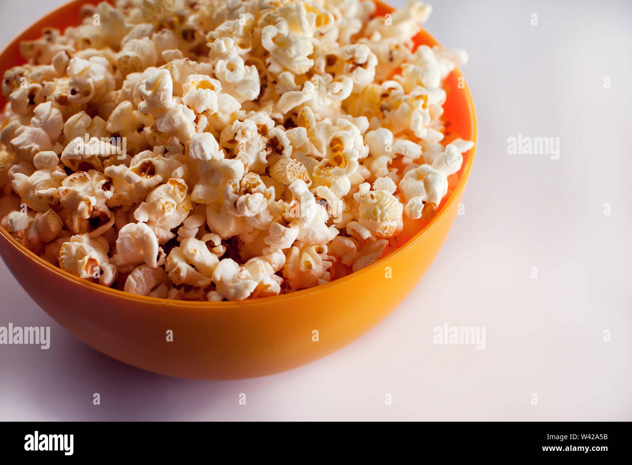 An orange bowl with popcorn isolated on white background. Food concept ...