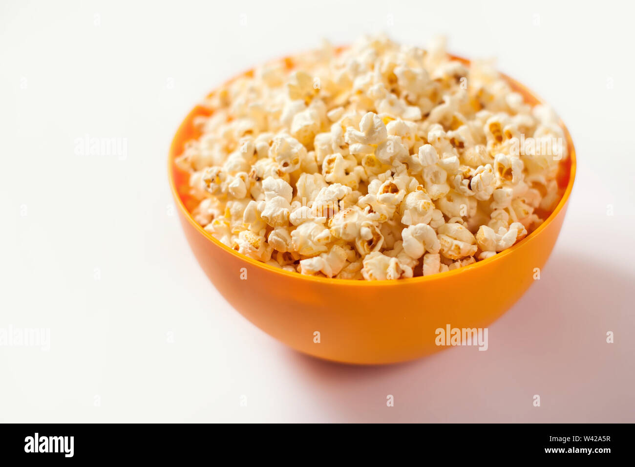 An orange bowl with popcorn isolated on white background. Food concept ...