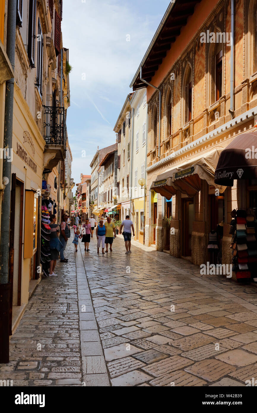 View of tourist and locals walking down cobbled lined with shops on ...