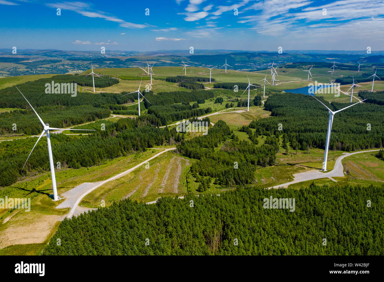 Aerial drone view of turbines at a large onshore windfarm on a green ...