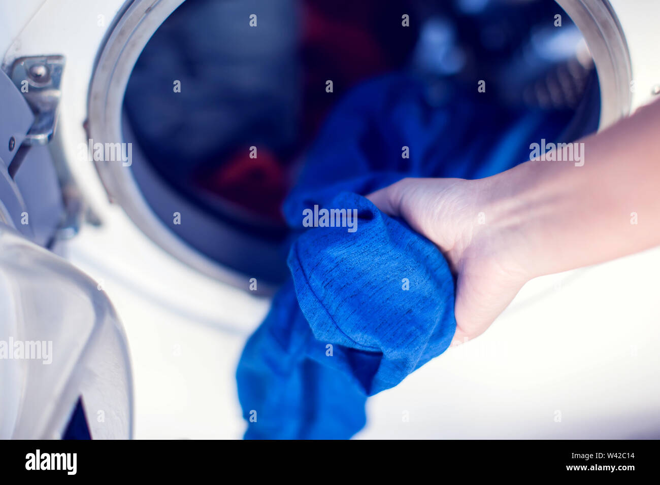 Close-up Of Person Hand Putting Dirty Clothes In Washing Machine For ...