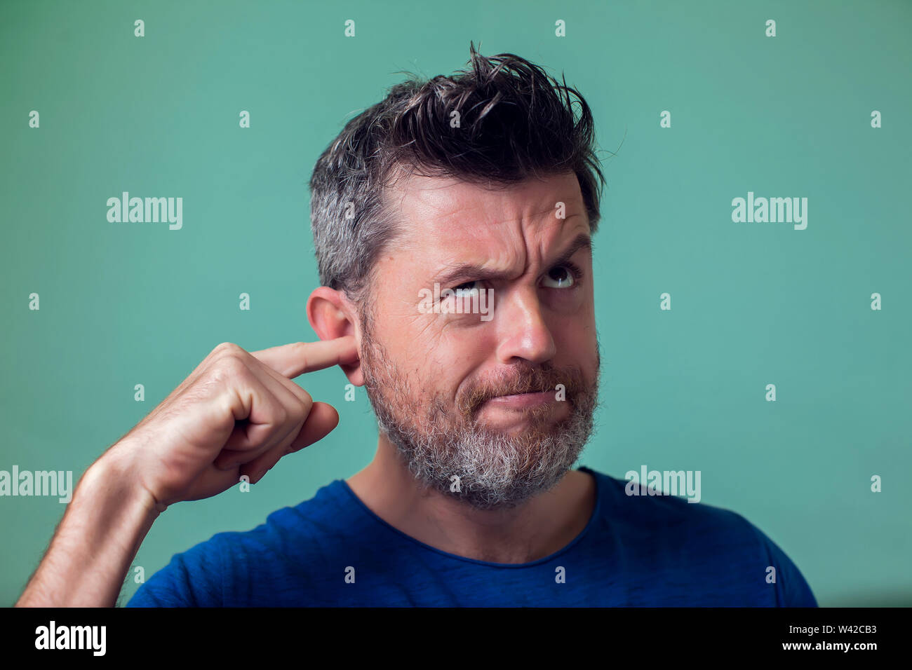 Young man with beard picking his ear with his finger- people ...