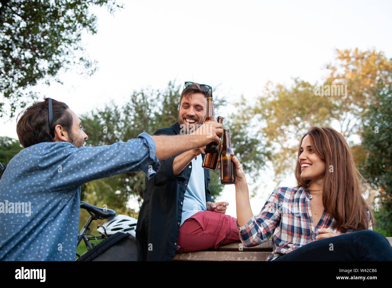 Three happy young friends tourists on a bench in a park in Rome having ...
