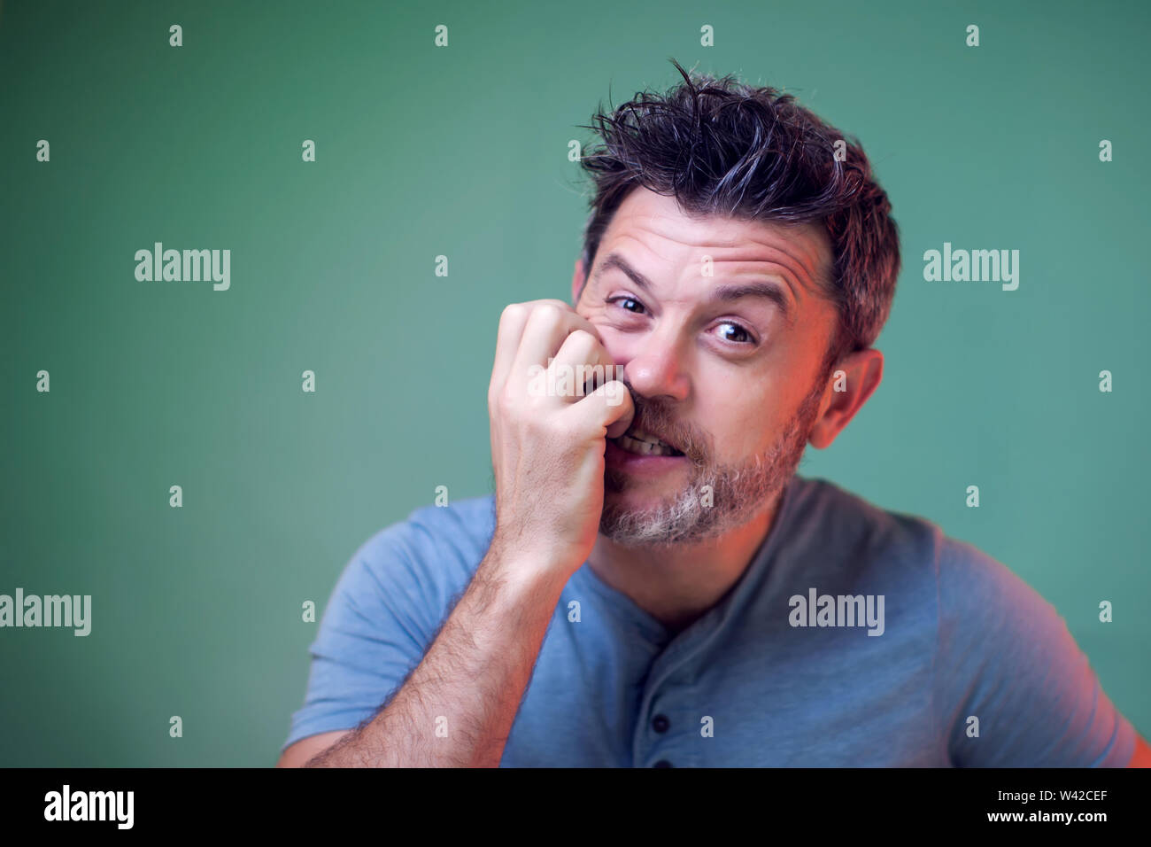 People and emotions - a portrait of nervous man with beard nail bitting ...