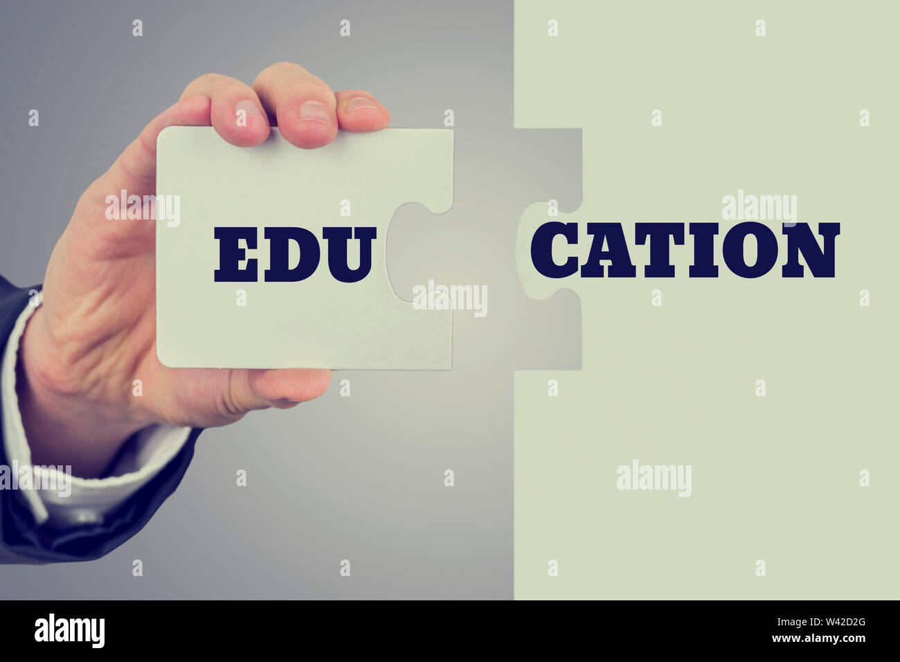 Male hand holding word Education split over two puzzle pieces ...