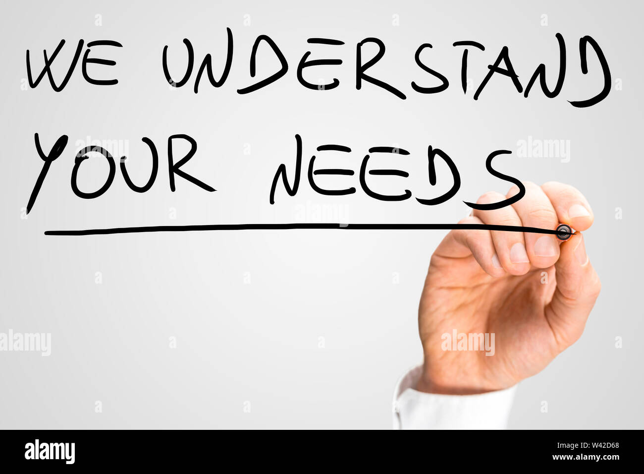 Businessman writing the message - We Understand Your Needs - with a ...