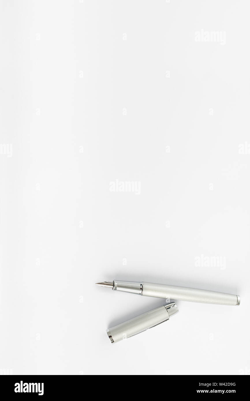 Top view of open ink pen lying on blank sheet of white paper with copy ...
