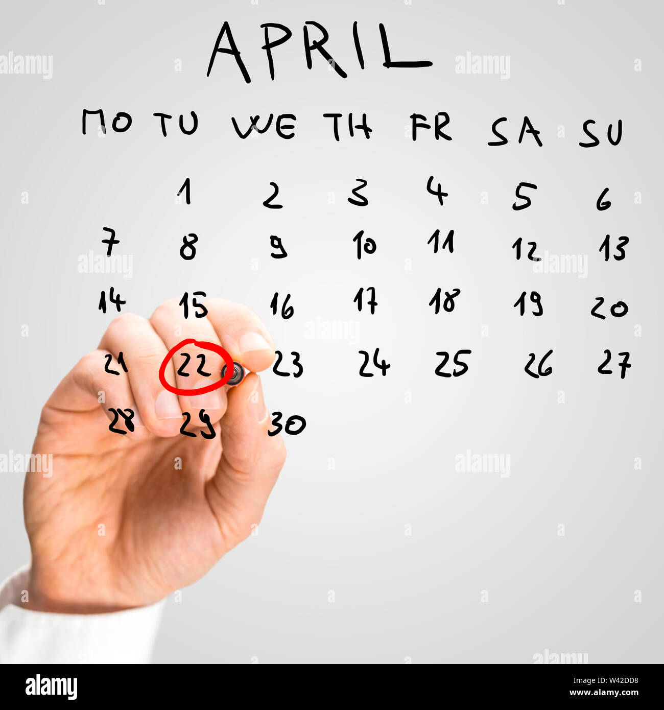 Male hand encircling the date of April 22 on a monthly calendar placed ...