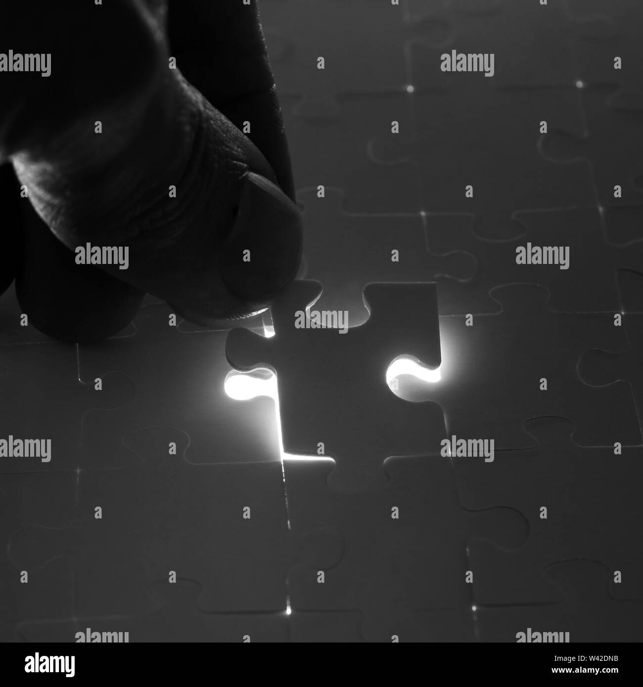 Man completing a jigsaw puzzle placing the last piece in position over ...