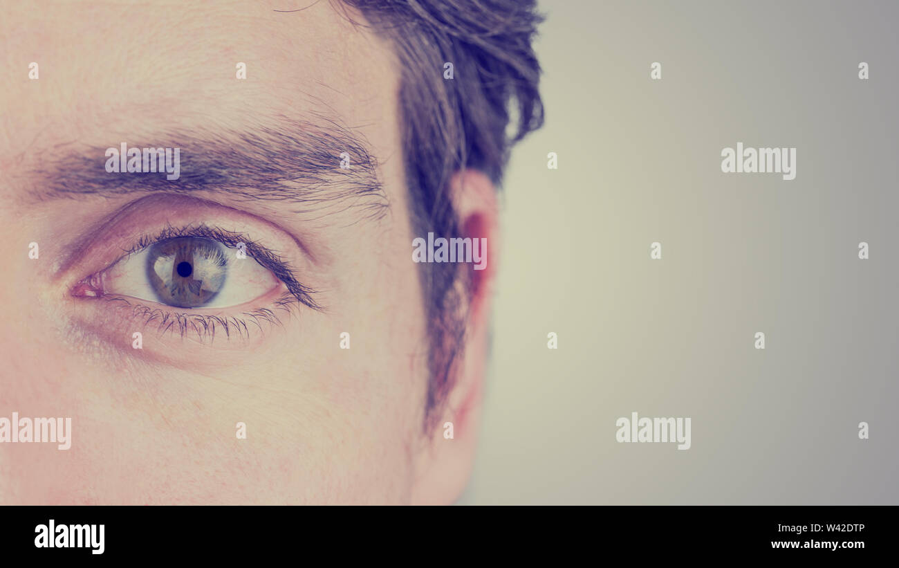 Close up of the eye and ear of a man looking straight ahead showing ...