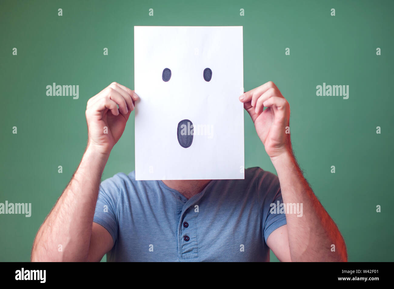 A portrait of man holding a card with scared face. People, emotions and ...