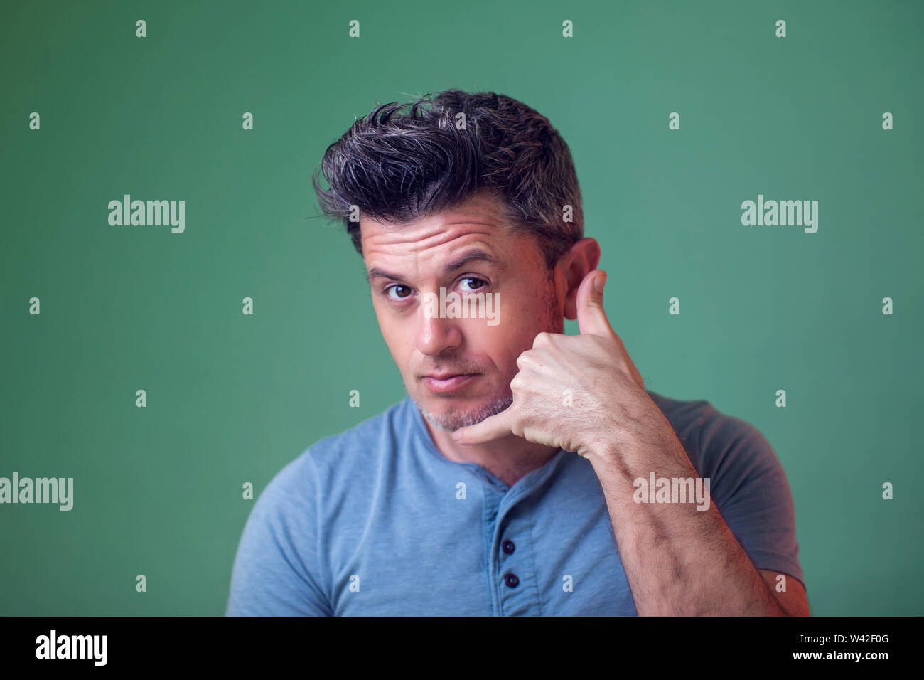 Portrait of serious handsome young man making a call me sign. People ...