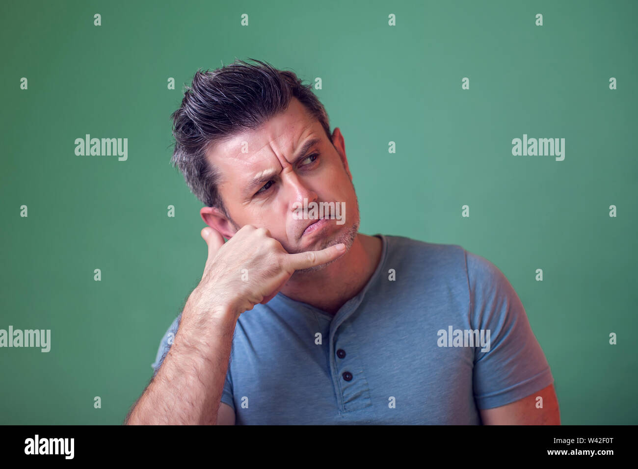 Portrait of serious handsome young man making a call me sign. People ...