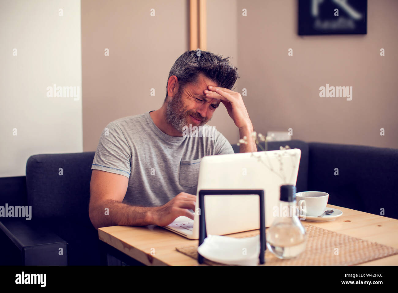 Man having a headache in front of laptop. People, health care and ...