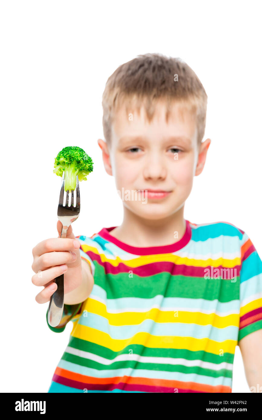 Vertical portrait of a boy with broccoli on a fork, vegetable in focus ...