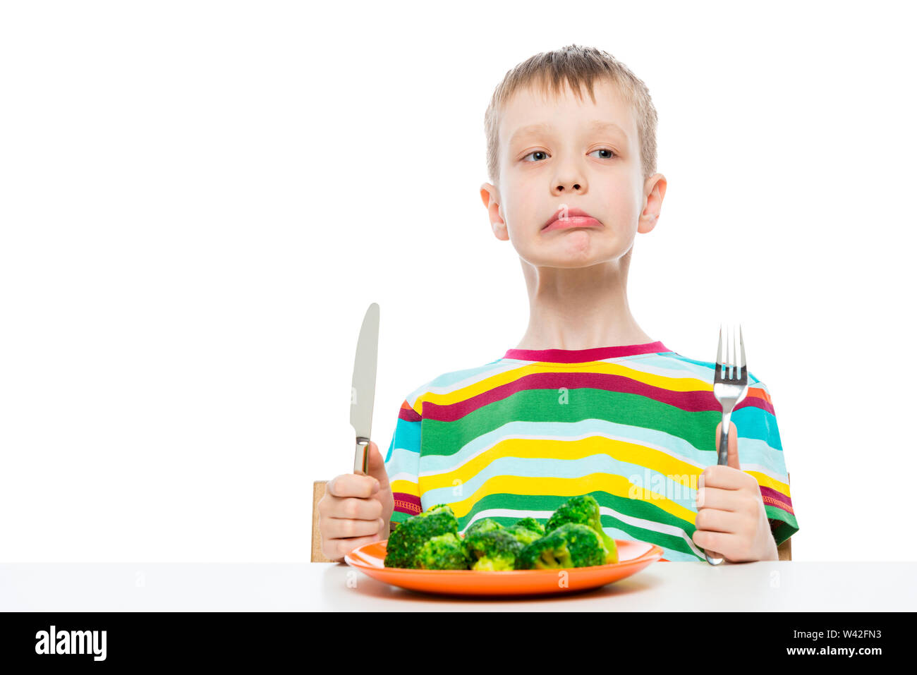 Boy disgusted with eating broccoli, portrait isolated on white ...
