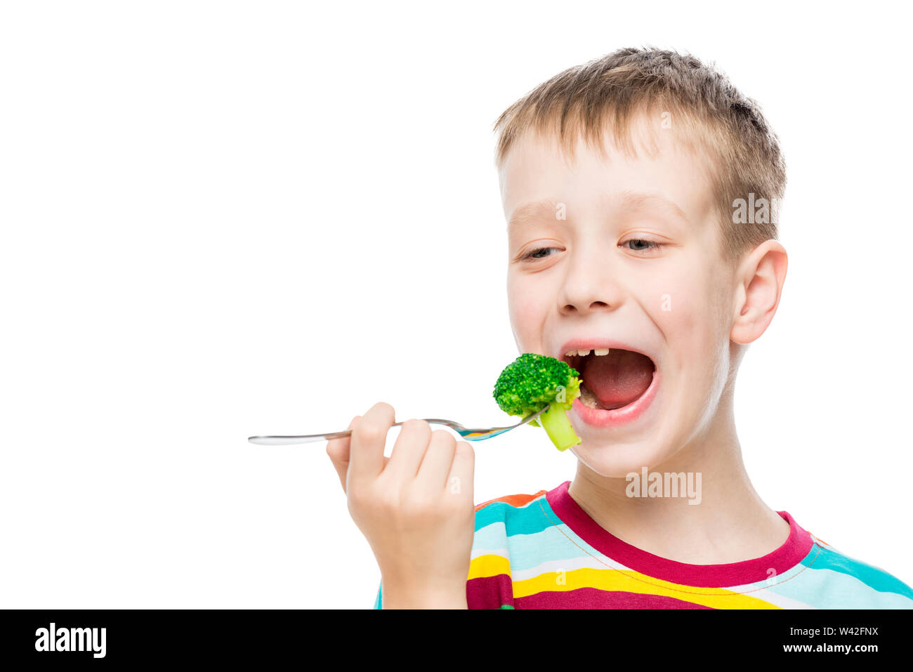 Portrait of a boy on a white background, the child eats broccoli Stock ...