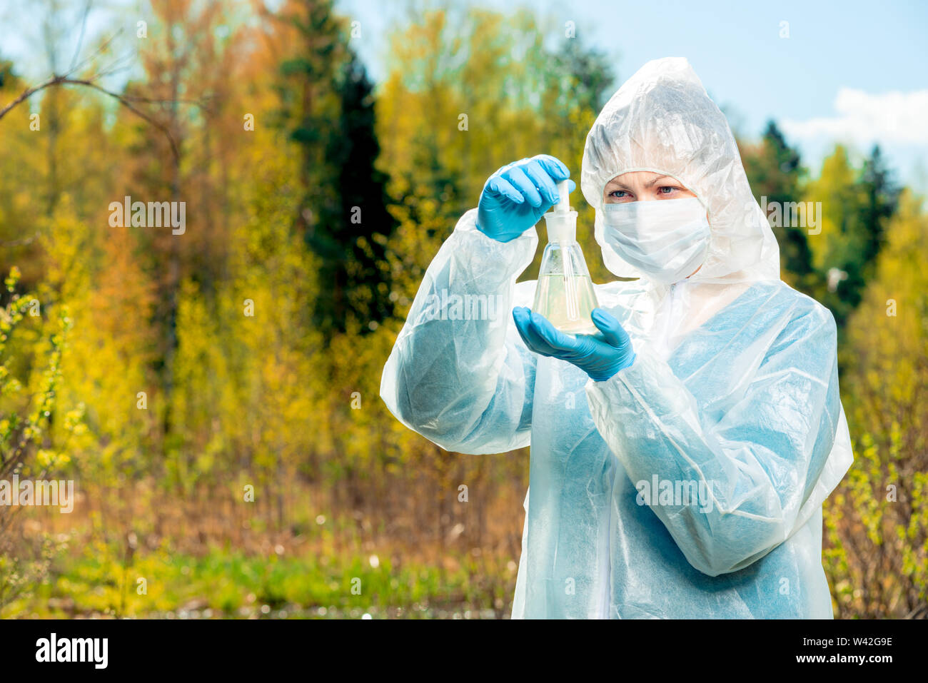 a scientist studies the composition of water from a forest lake in ...