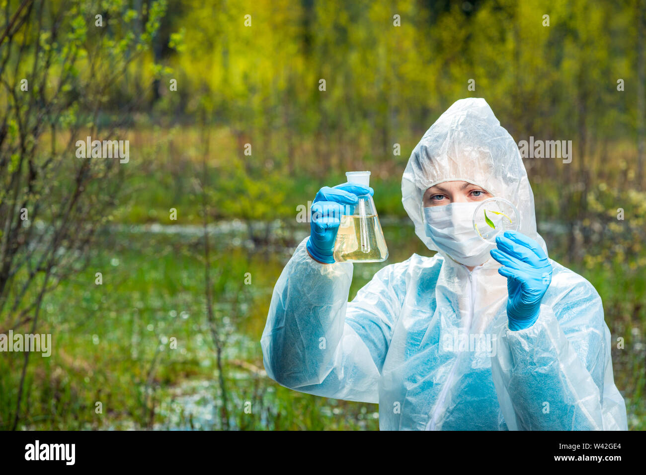 Ecologist with samples of water and plants from the forest river ...