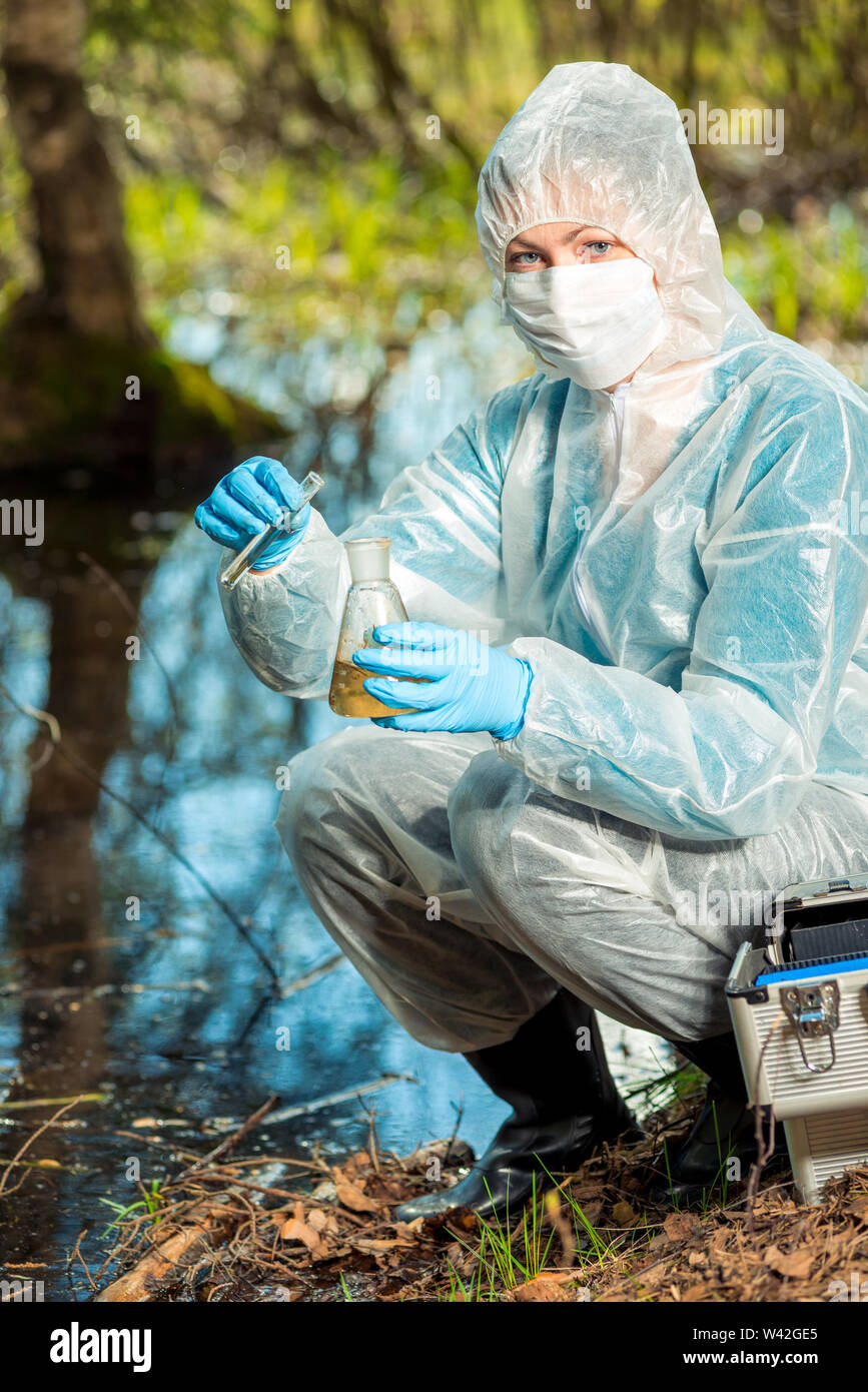 ecologist and with test tubes and flasks analyzes water in a forest ...