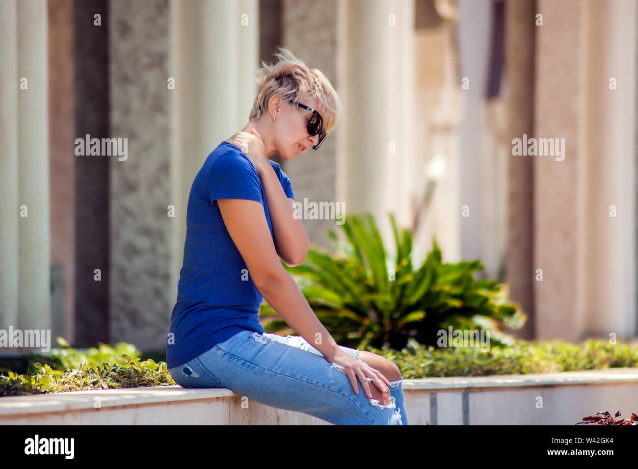 Woman holding her neck feeling pain while walking on the street. Health ...