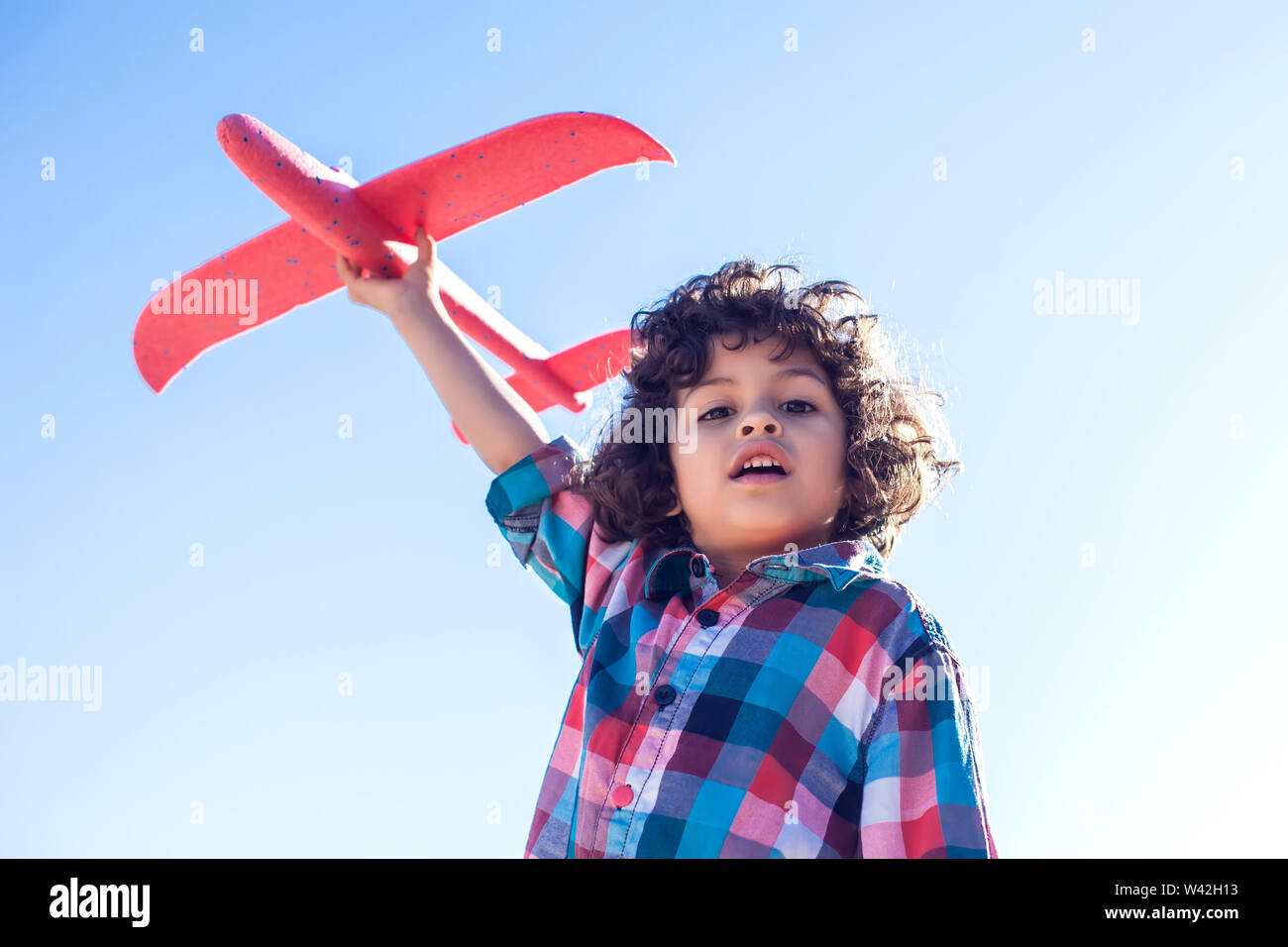 Young happy boy playing with red airplane outdoor. Children and ...