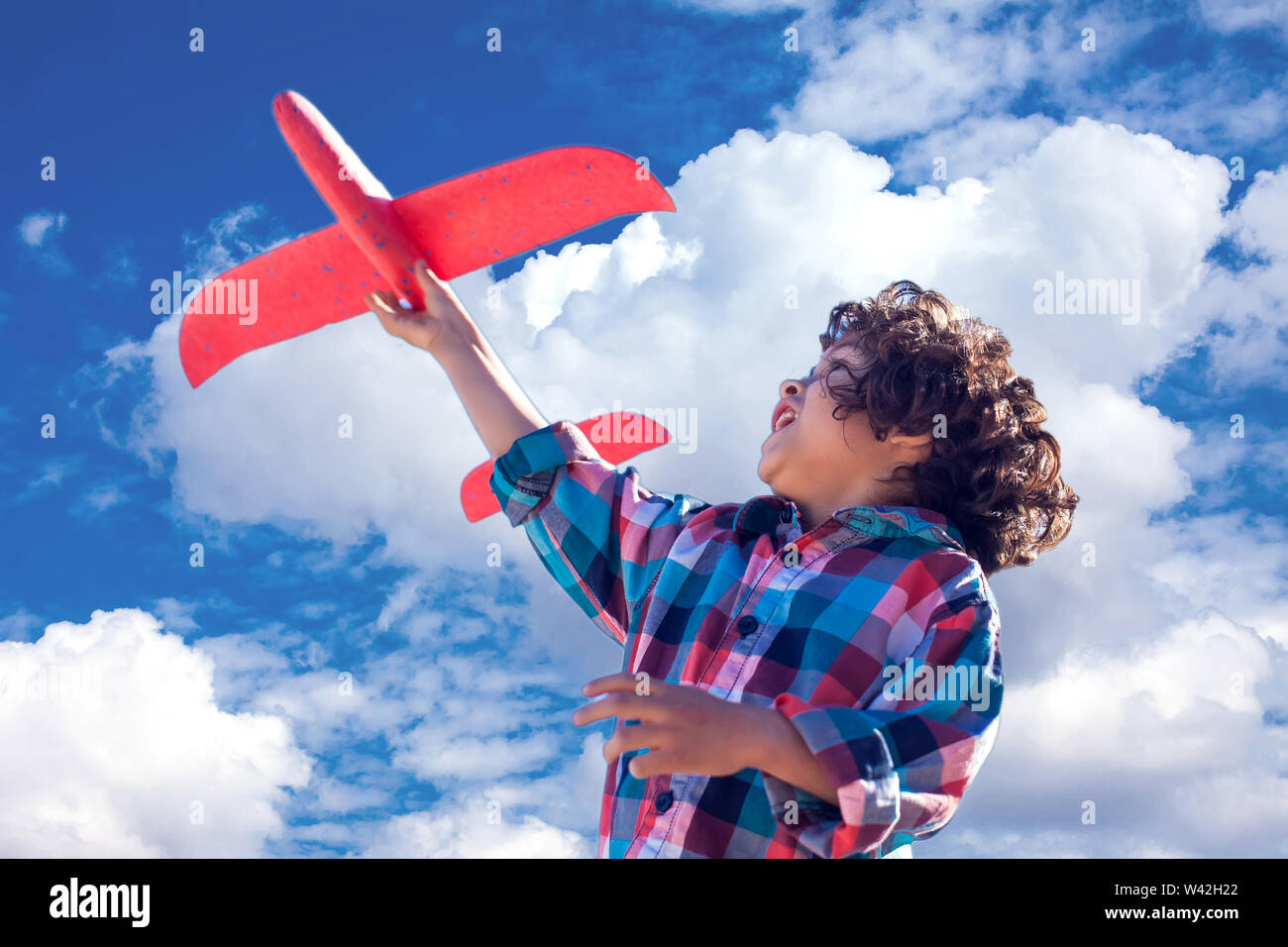 Young happy boy playing with red airplane outdoor. Children and ...