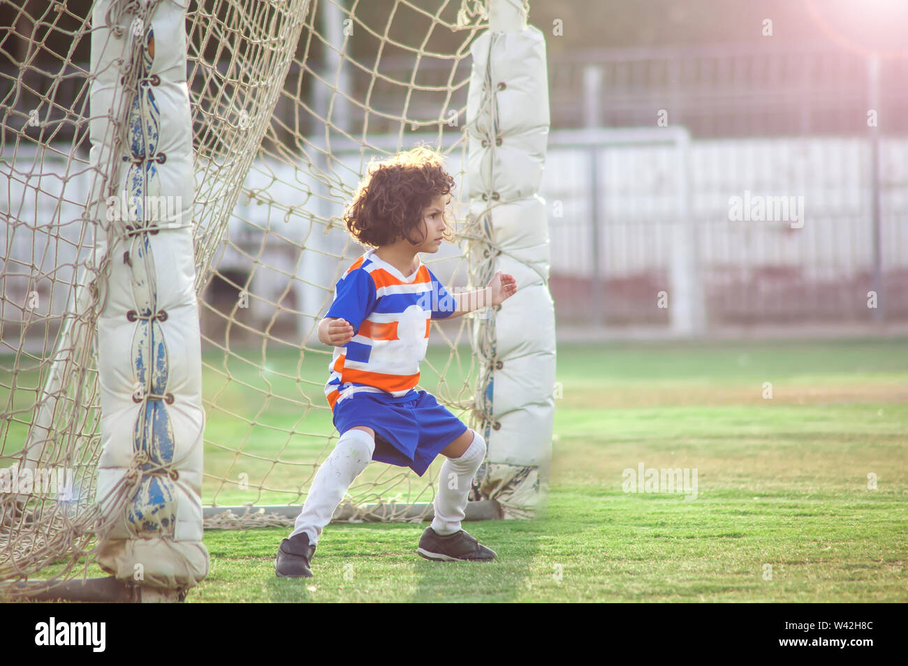 Little boy goalkeeper used hands for catches the ball in match game ...