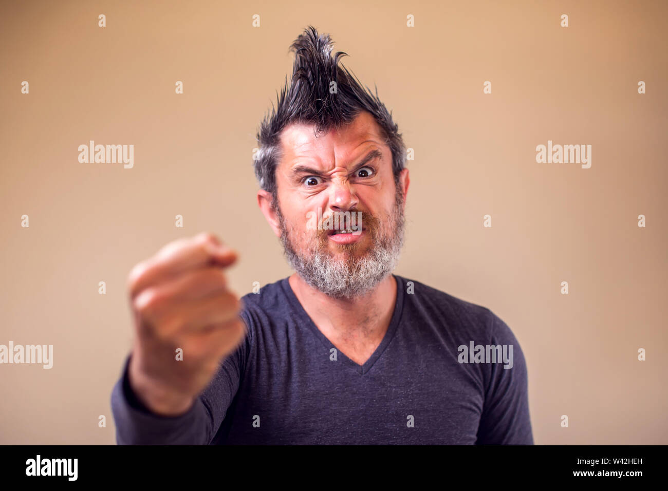 Closeup portrait of an angry adult man with a beard and iroquois shows ...