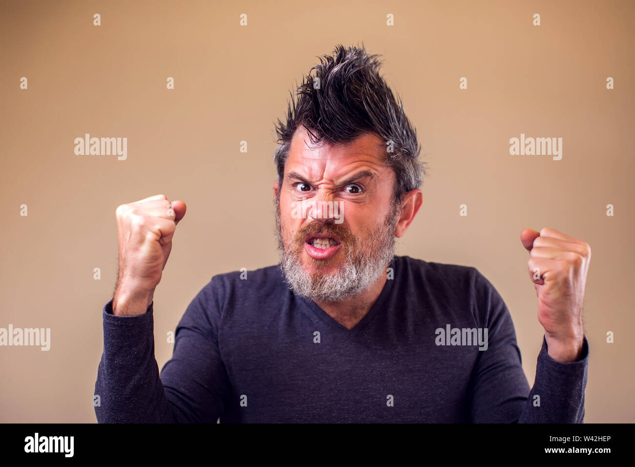 Closeup portrait of an angry adult man with a beard and iroquois shows ...
