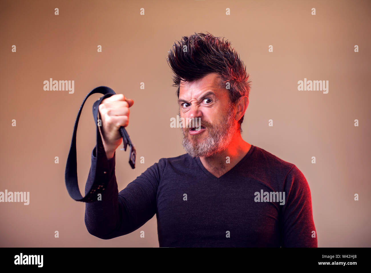 Angry bearded man holds belt in hand. Emotions and family violence ...