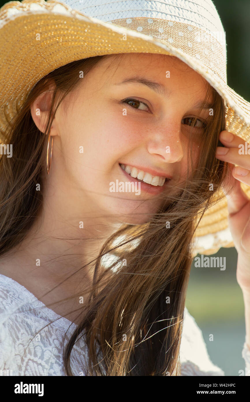 pretty girl in sun hat in sun light looking at camera, laughing toned ...