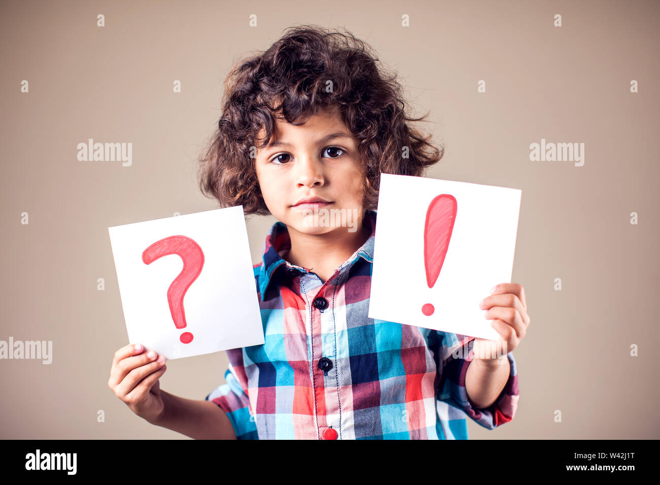 Thinking kid boy holds question and exclamation signs Stock Photo - Alamy