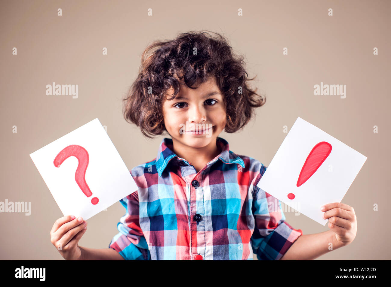 Thinking kid boy holds question and exclamation signs Stock Photo - Alamy