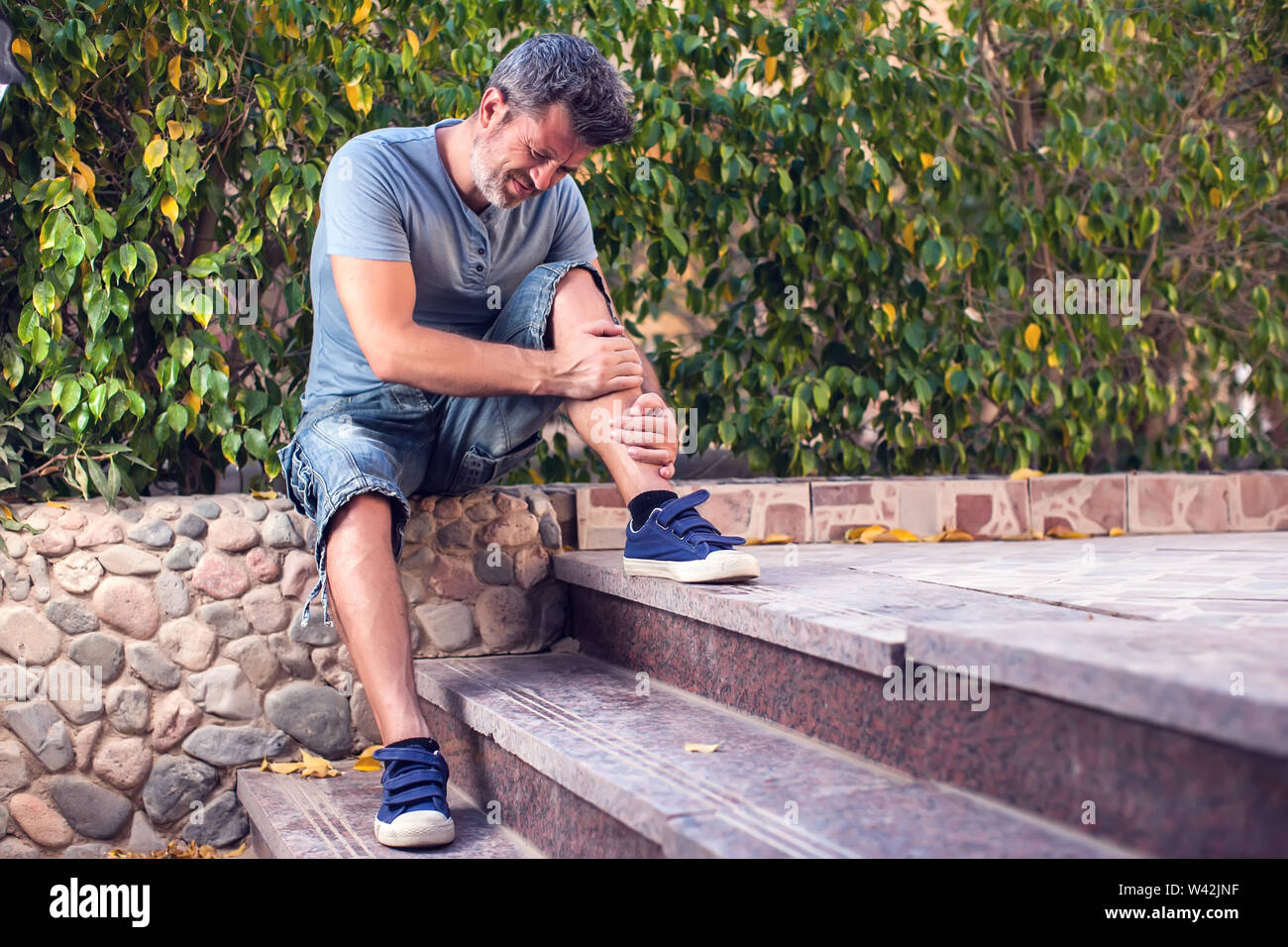 Man feels strong foot pain while walking outdoor. People, healthcare ...