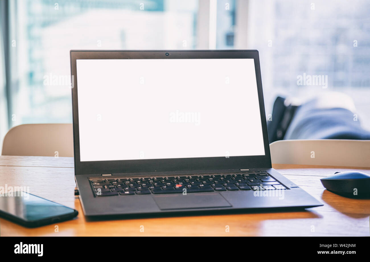 Blank screen computer laptop on a wooden desk, blur winddow background ...