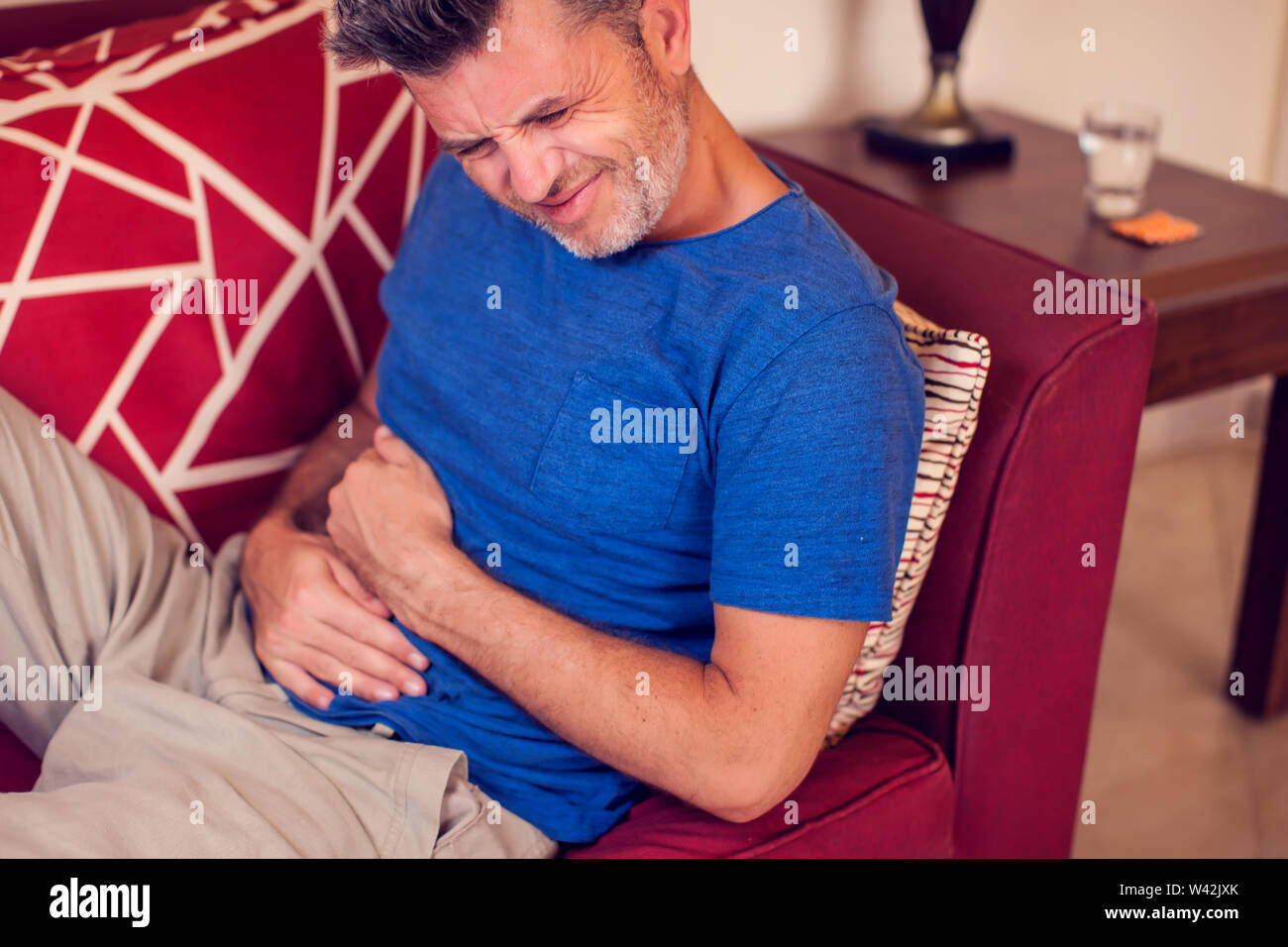 Man feels strong stomach pain at home. People, healthcare and medicine ...