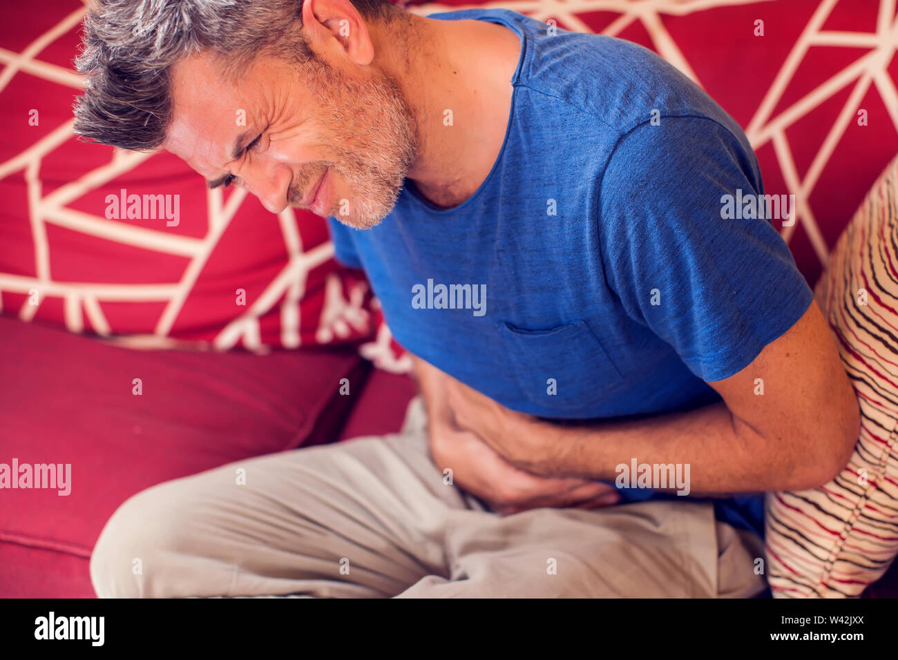 Man feels strong stomach pain at home. People, healthcare and medicine ...
