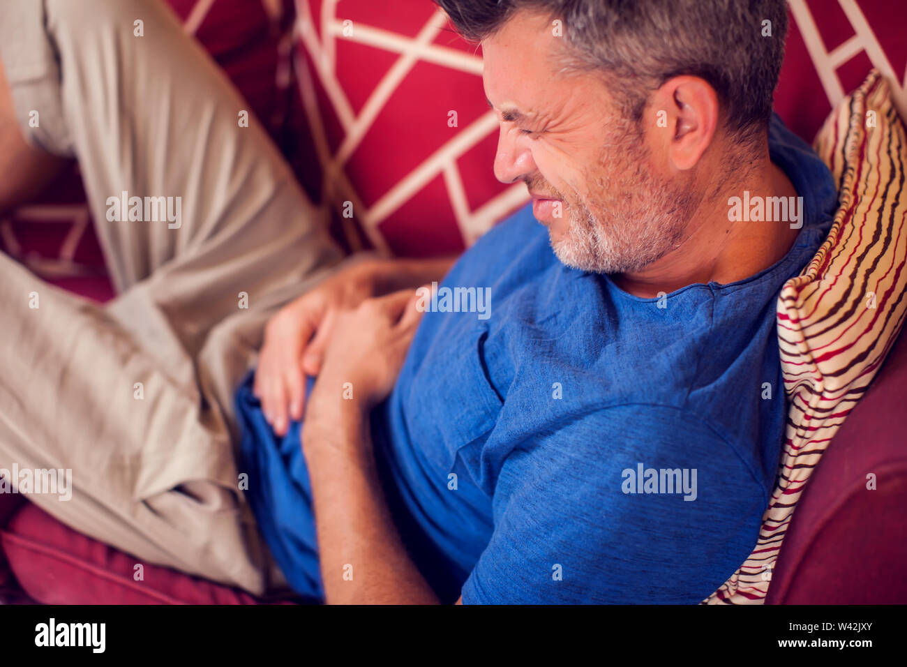 Man feels strong stomach pain at home. People, healthcare and medicine ...