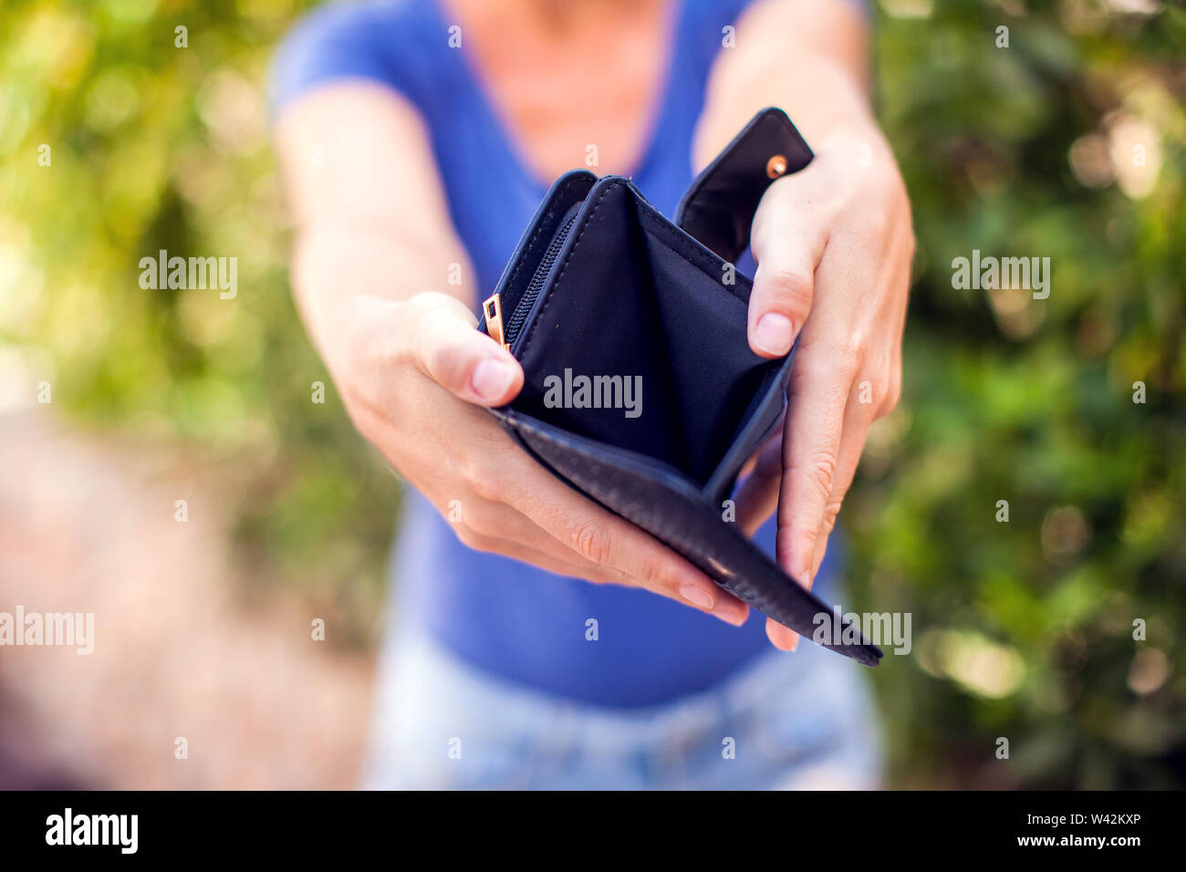 Woman holds an empty wallet in hands outdoor. Finance problem concept ...