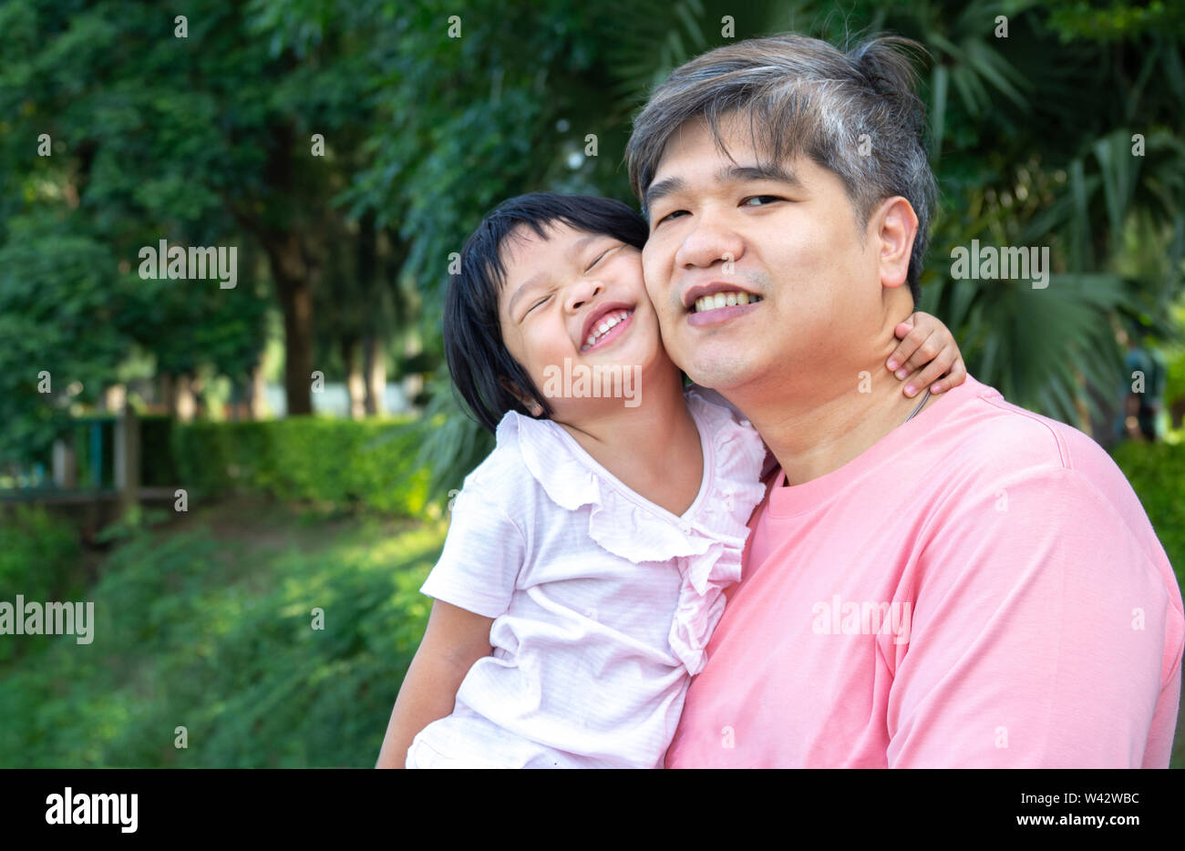 An Asian father is carrying a lovely daughter to her chest. Both the ...