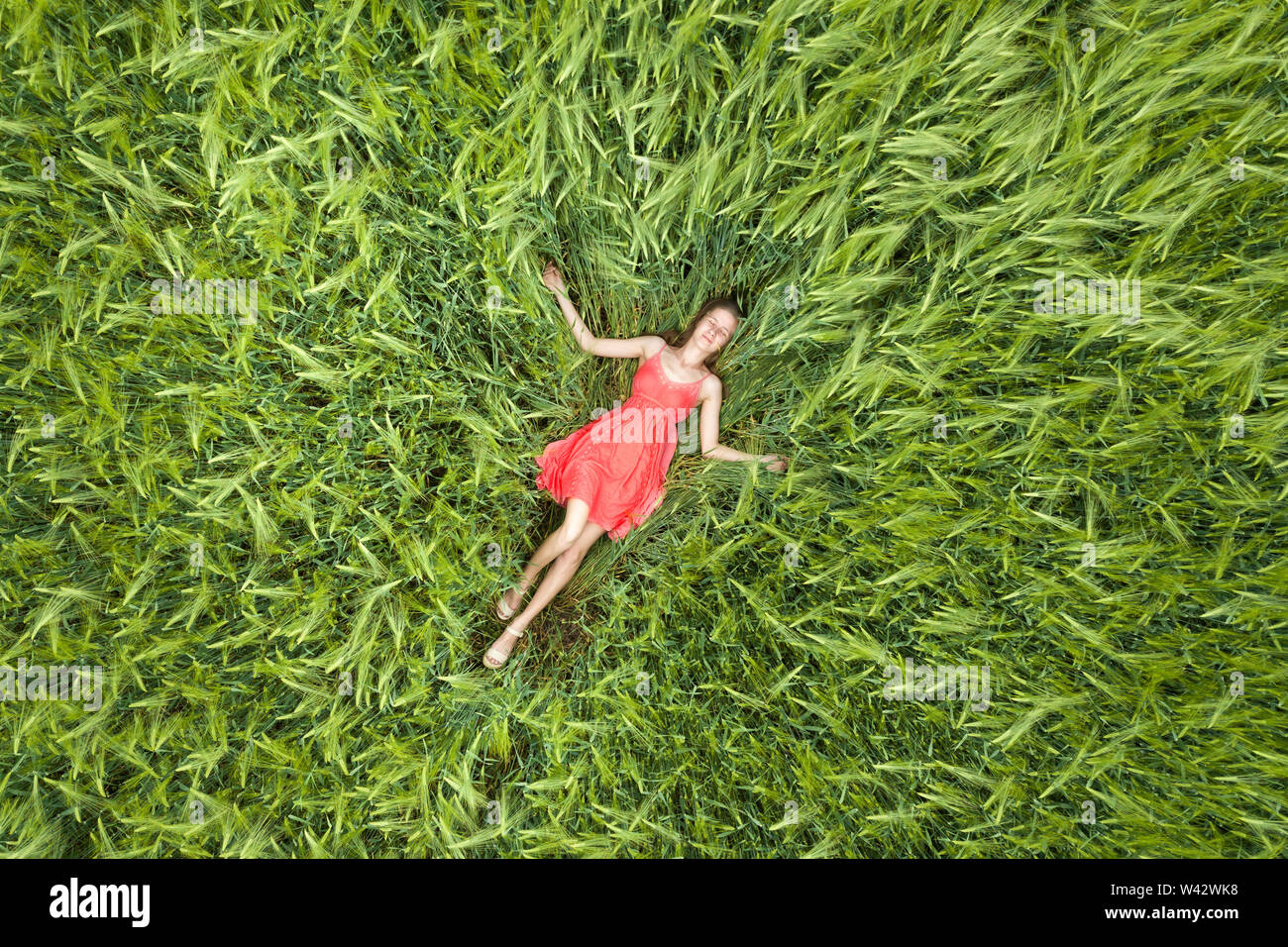 View from above of young attractive slim woman in red dress laying with ...