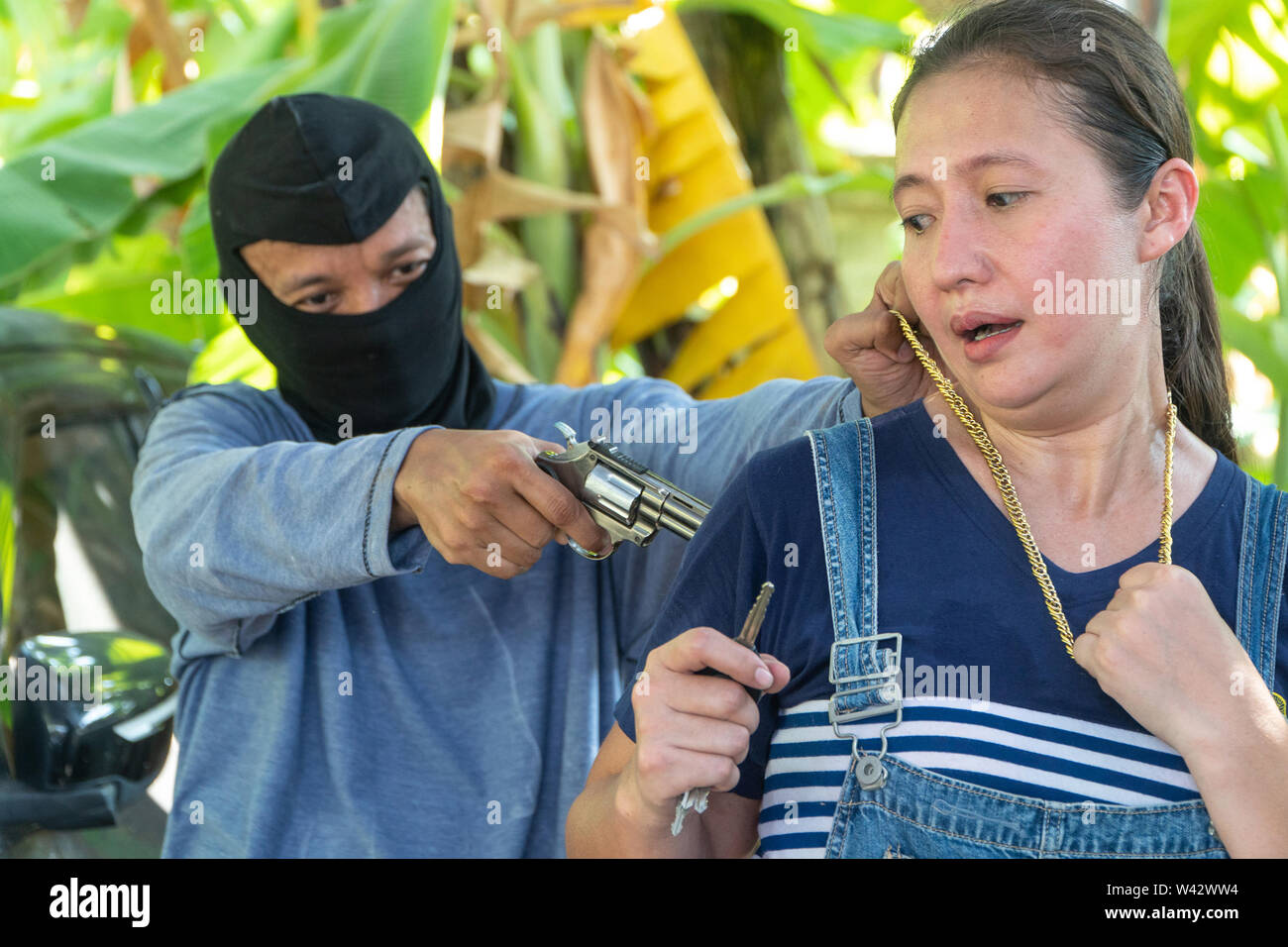 Man with masked robber and threatening with gun to scared woman in car ...