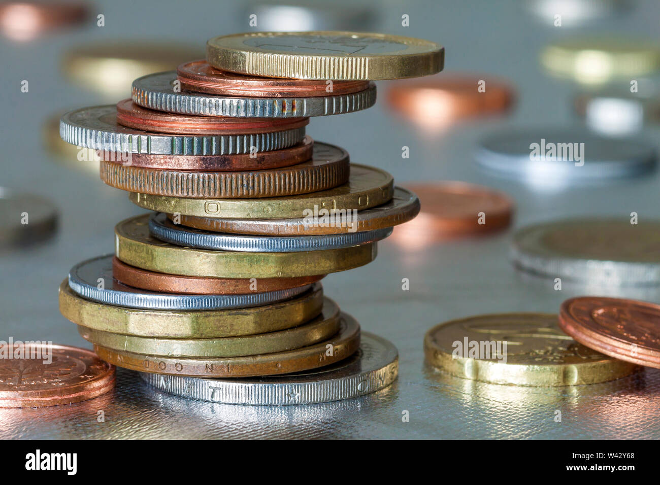 Two piles of shiny coins different sizes and colors stacked unevenly on ...